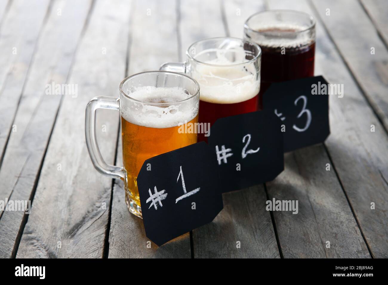 Glass mugs with different sorts of craft beer and numbering on wooden ...
