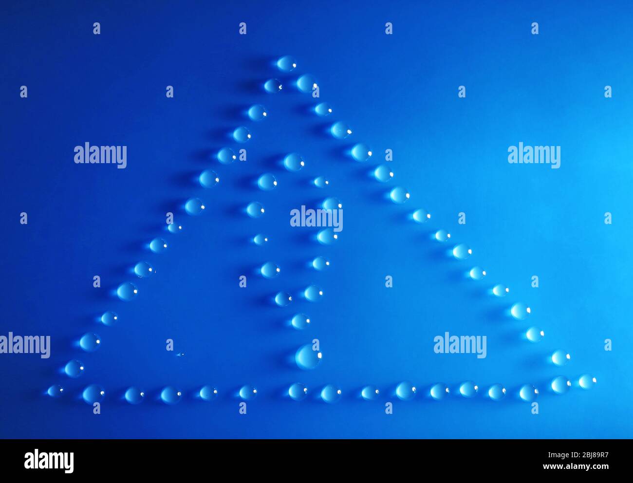 Triangle and exclamation mark made of water drops on blue background ...