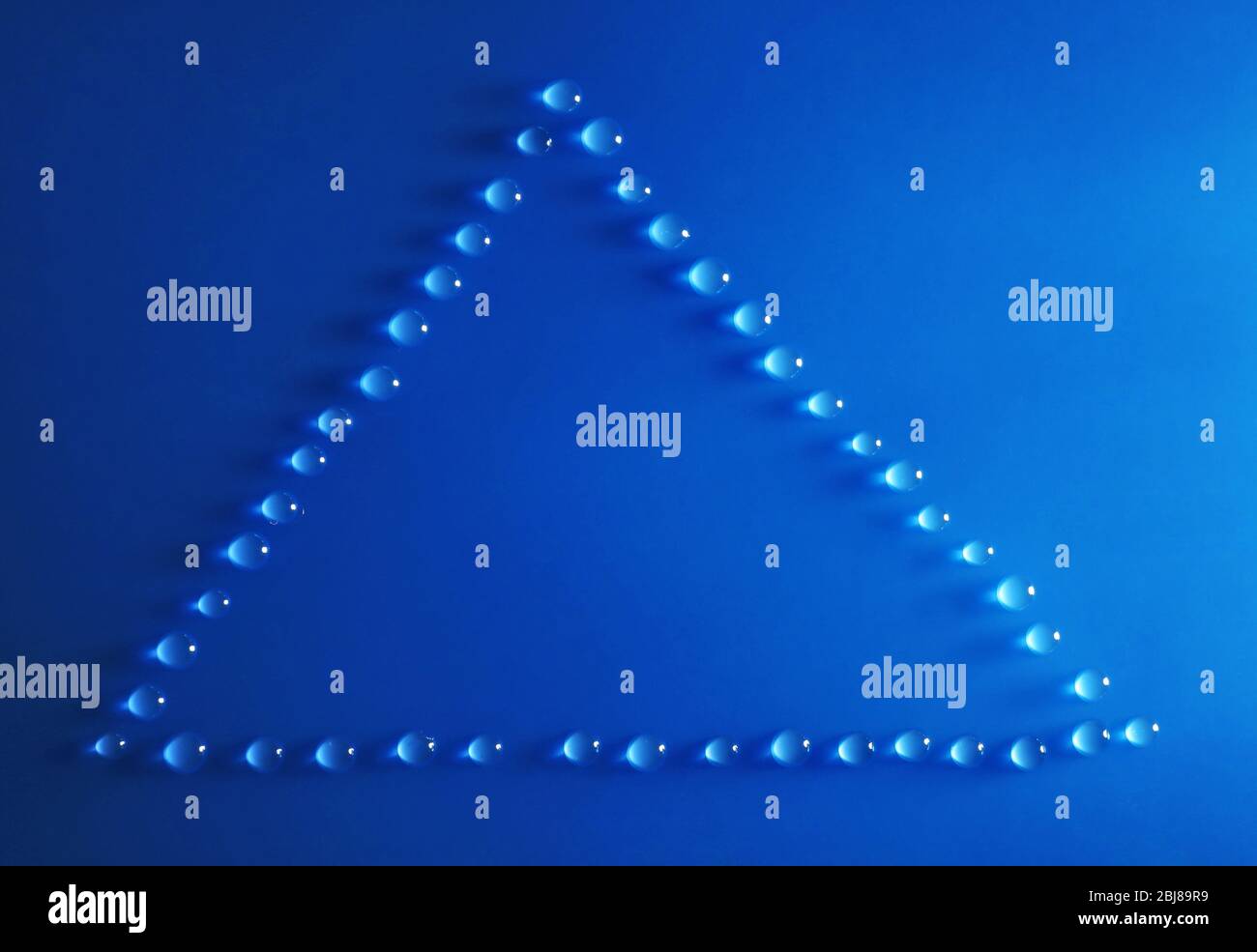 Triangle made of water drops on blue background Stock Photo - Alamy