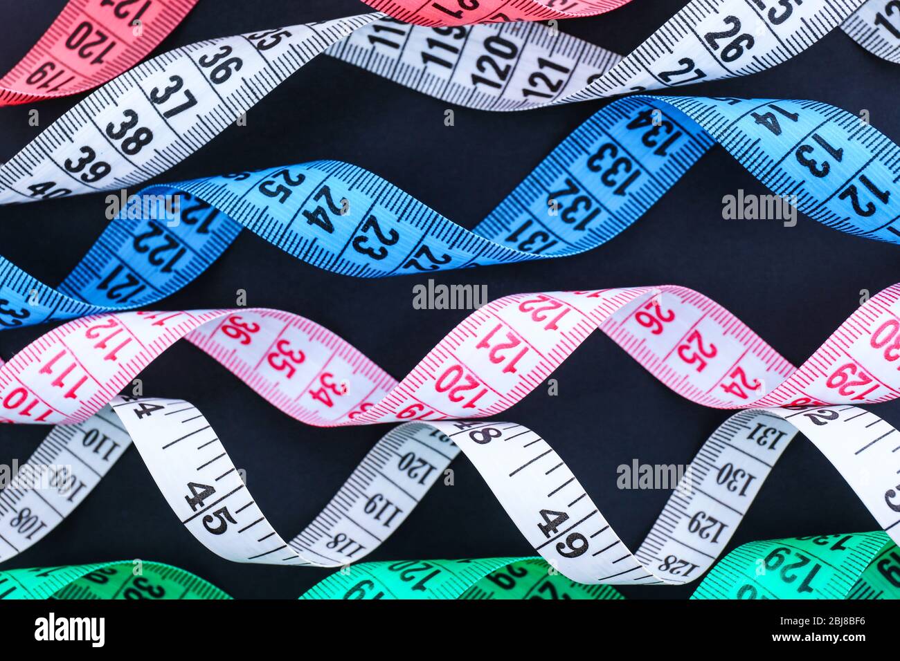 Colorful measuring tapes on a black background Stock Photo - Alamy