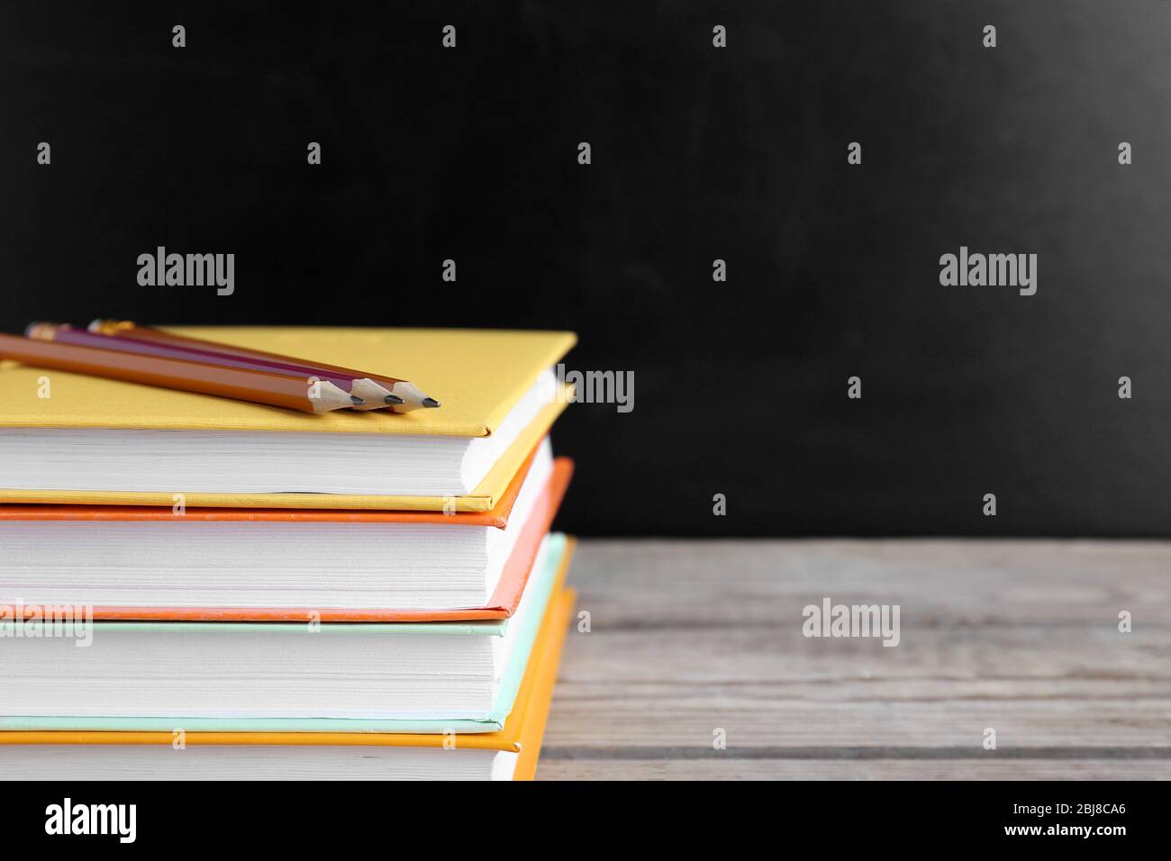 Few books with pencils on table Stock Photo - Alamy