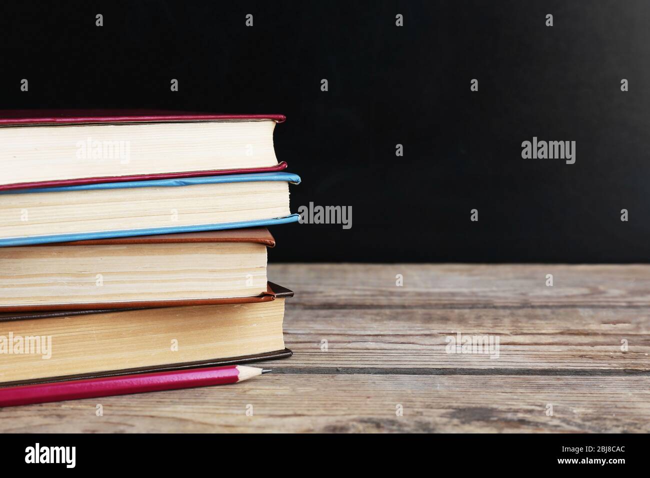 Few books with pencil on table Stock Photo - Alamy