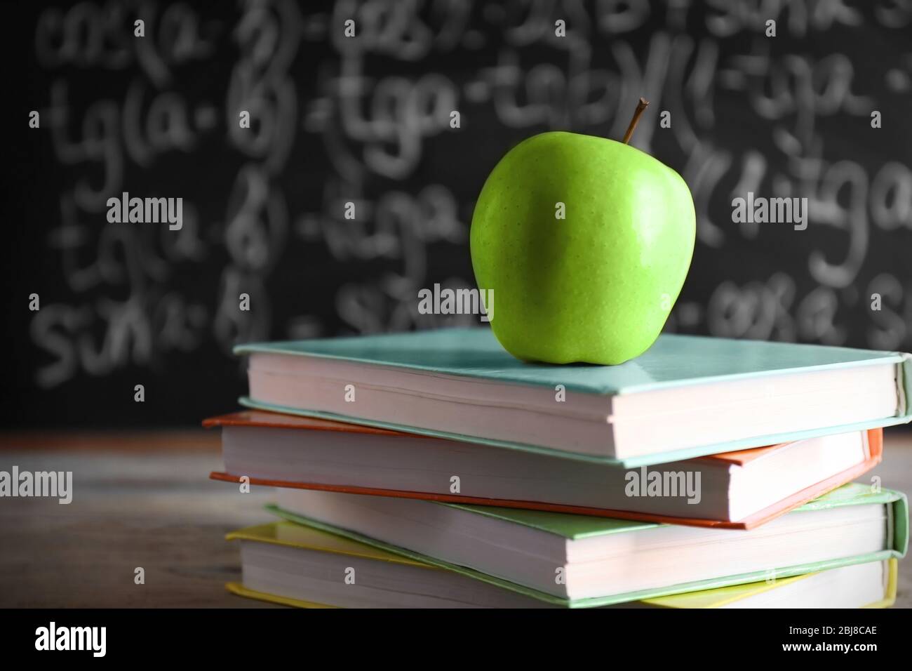 Few books with green apple on table Stock Photo - Alamy