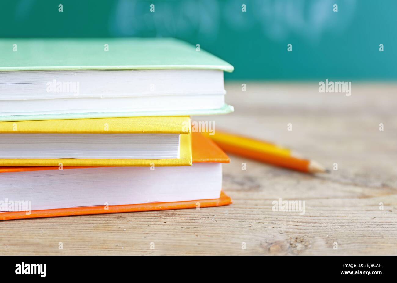 Few books with pencil on table Stock Photo - Alamy