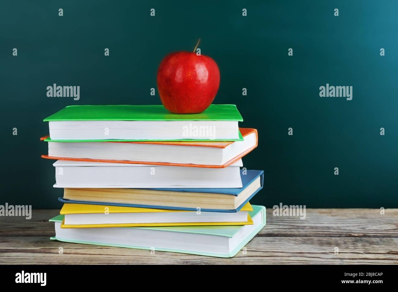 Few books with red apple on table Stock Photo - Alamy