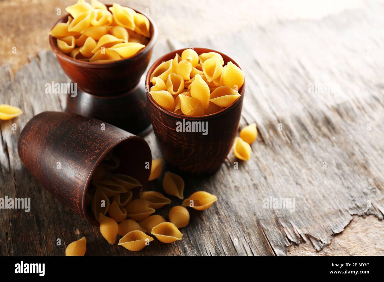 Raw pasta in cups on table Stock Photo - Alamy