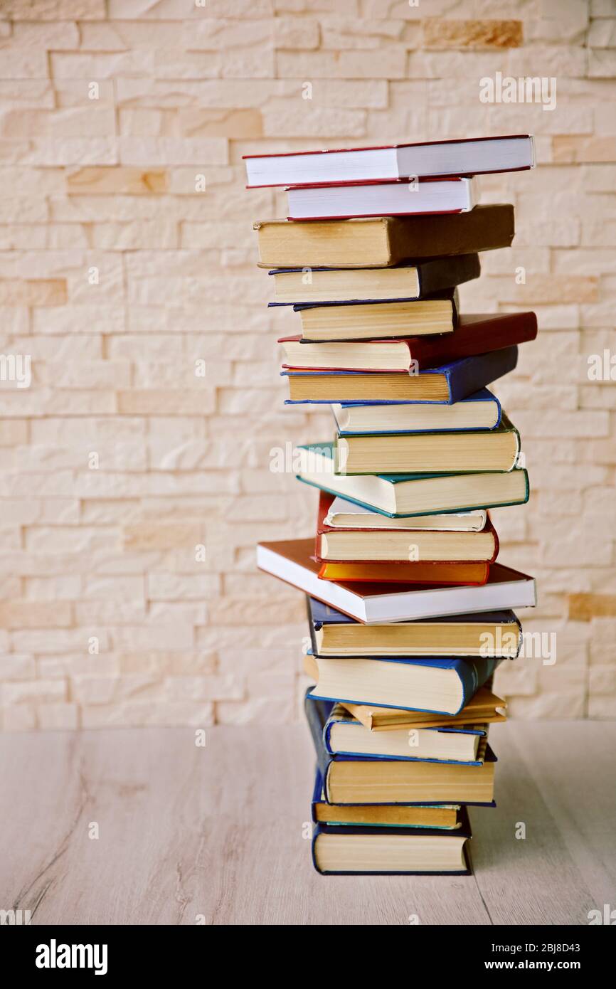 Pile of books on brick wall background Stock Photo - Alamy