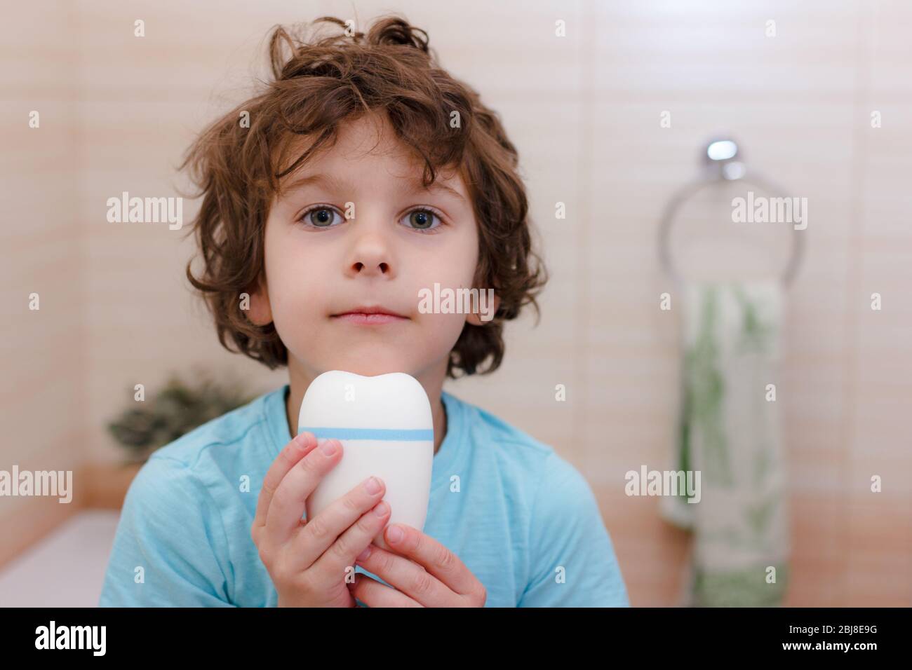cute curly boy holds big tooth in bathroom. The concept of children's ...