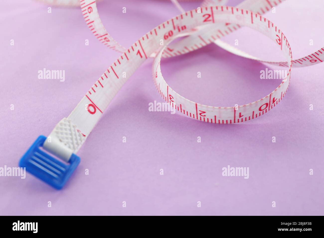 Measuring tape on purple background Stock Photo - Alamy