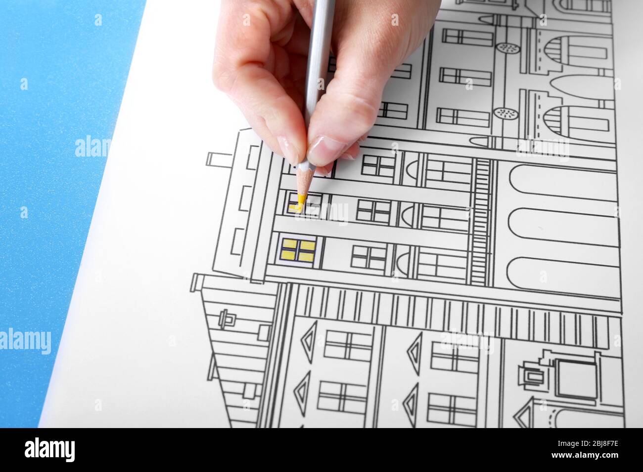 Female hand drawing with crayon in adult anti stress coloring closeup ...