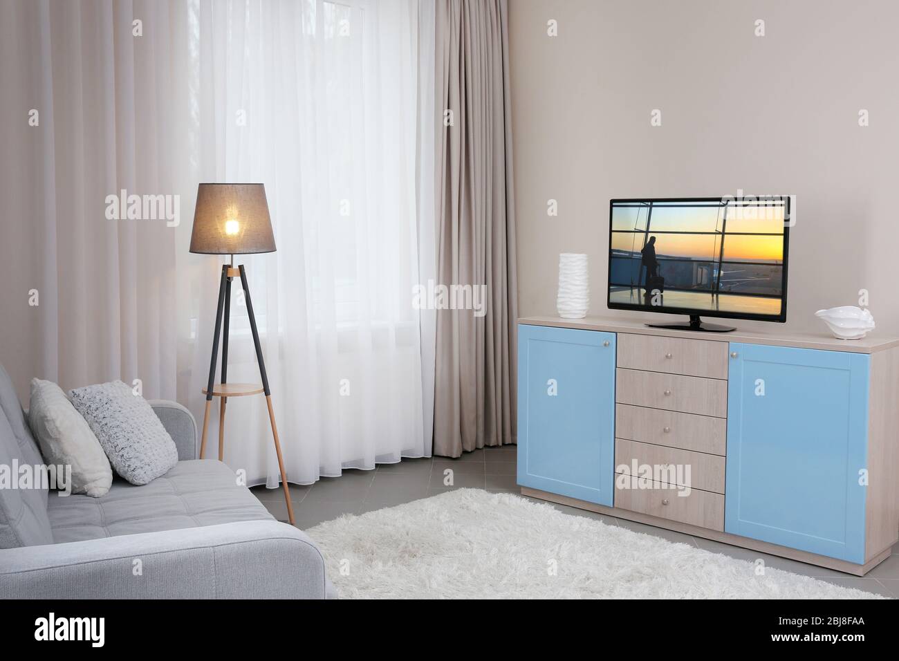 Modern living room with couch and TV Stock Photo - Alamy