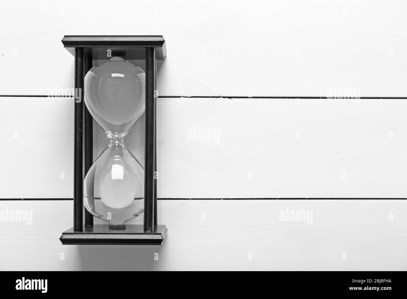 Black sand glass on white wooden background Stock Photo - Alamy