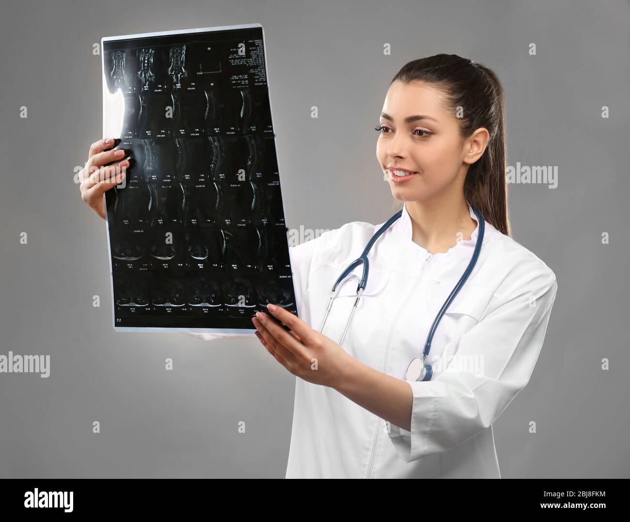 Young female doctor holding MRI scan on grey background Stock Photo - Alamy