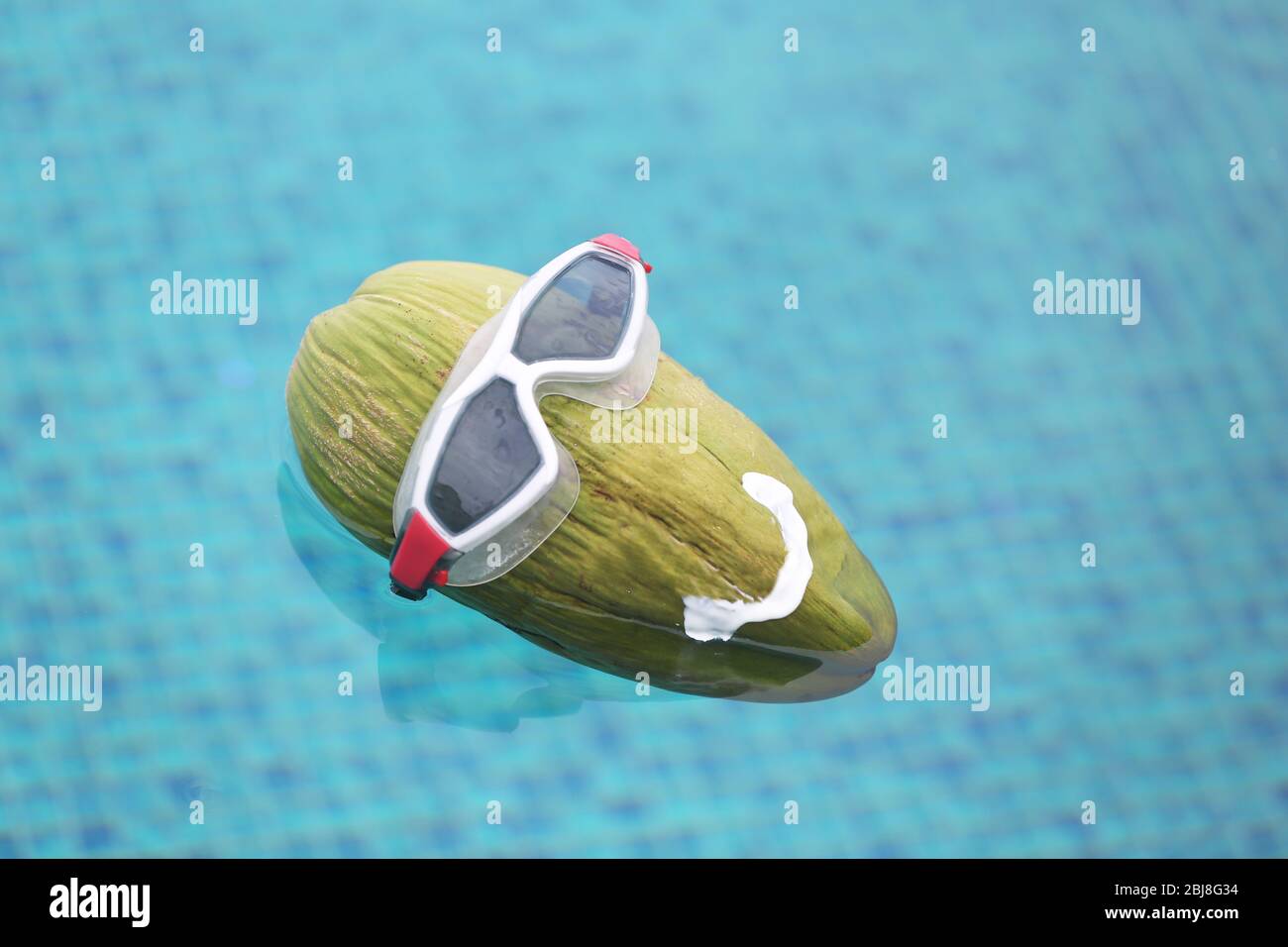 Green coconut in diving goggles floating in the pool Stock Photo - Alamy