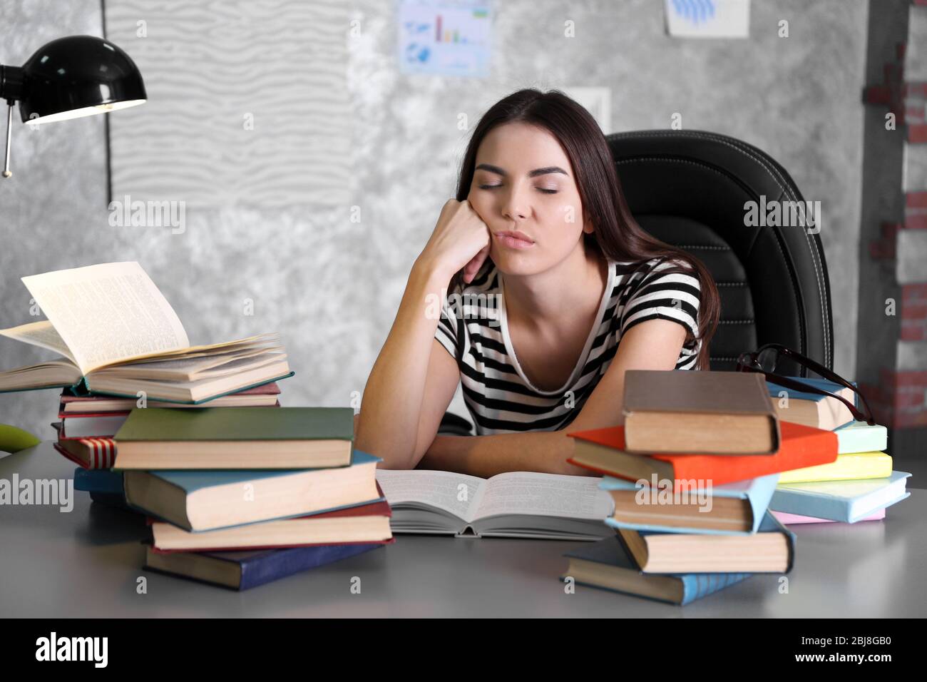 Young woman with books falling asleep at the table Stock Photo - Alamy