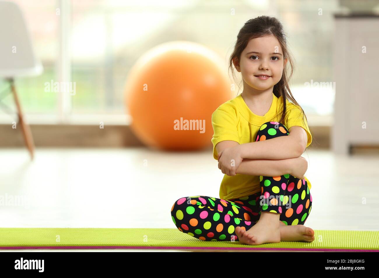 Little cute girl sitting on a mat indoor Stock Photo - Alamy
