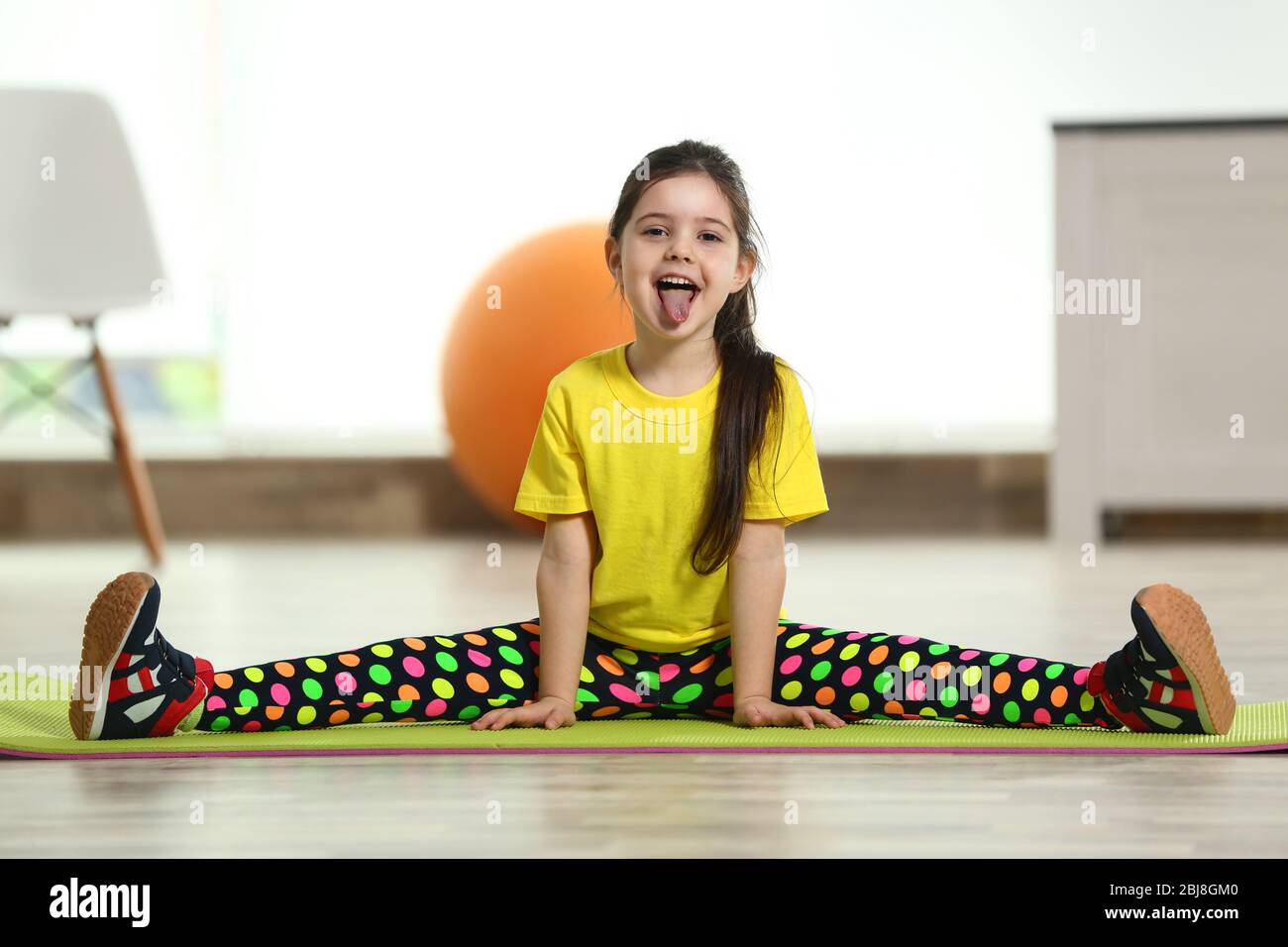 Little funny girl sitting in the splits on a mat indoor Stock Photo - Alamy