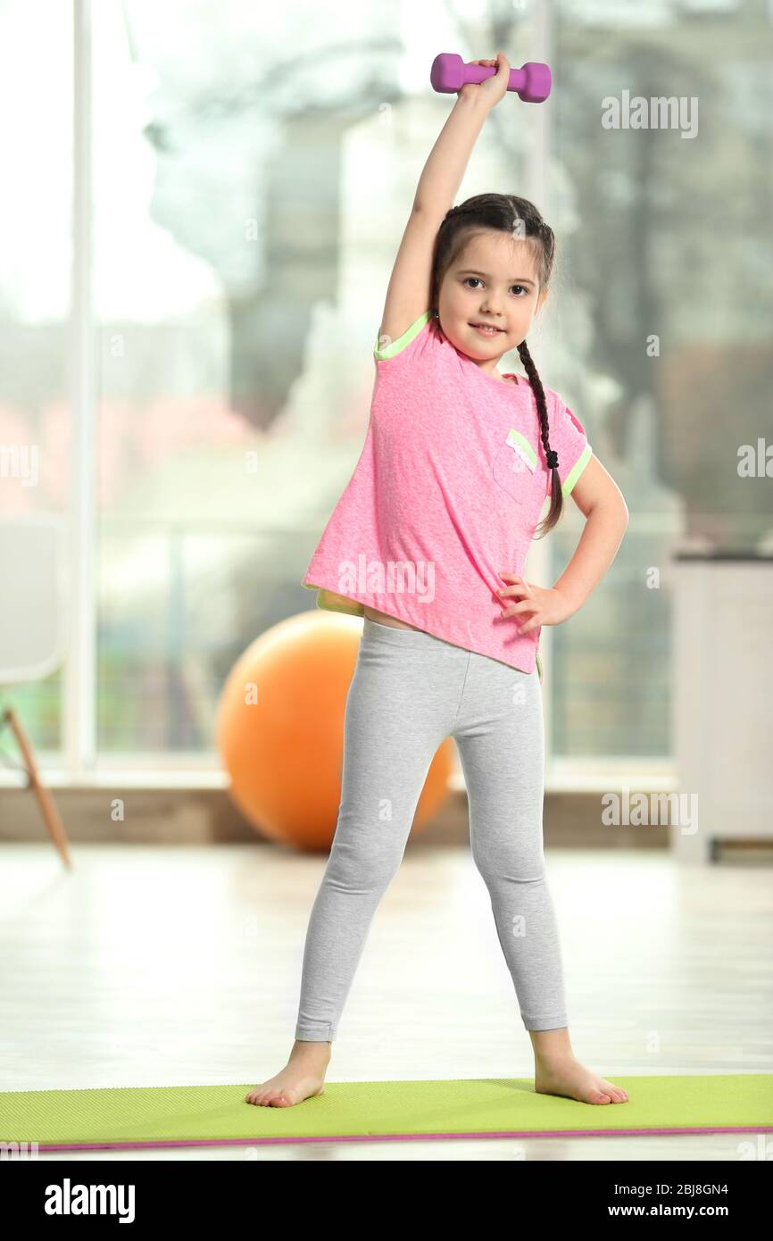 Little cute girl doing exercises with dumbbells on a mat indoor Stock ...