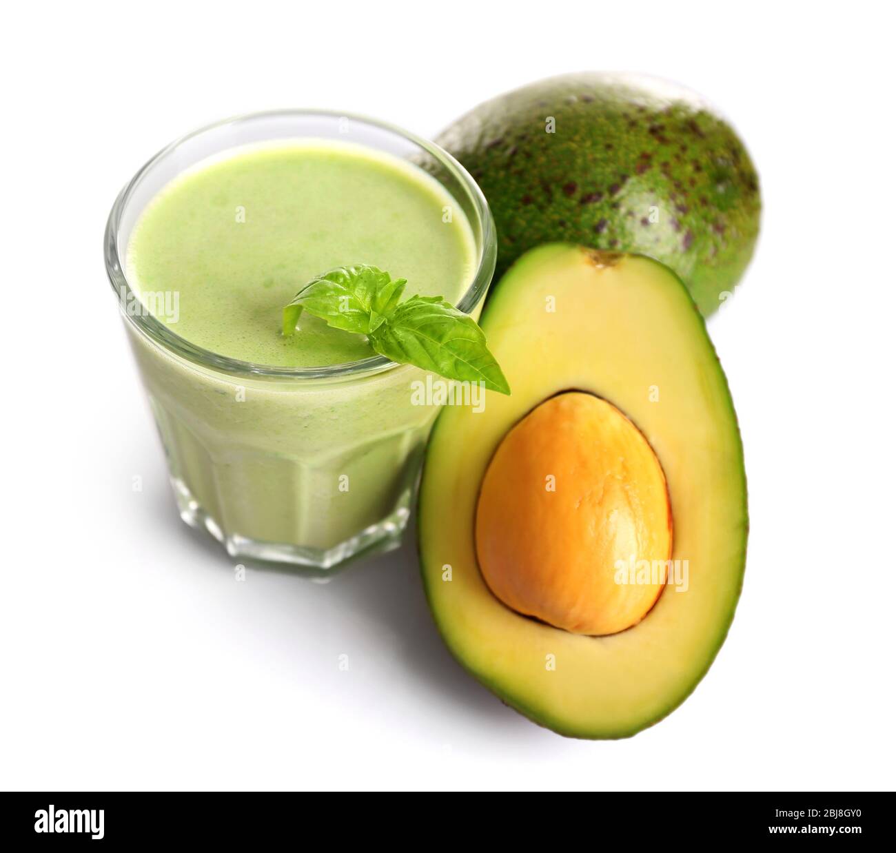 Glass of fresh avocado smoothie and avocado fruit isolated on white ...