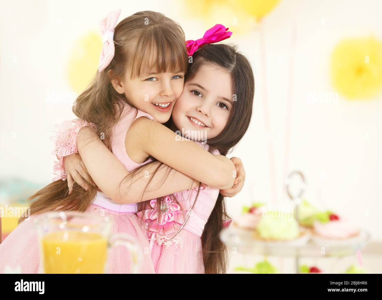 Happy little girls hugging at birthday party Stock Photo - Alamy