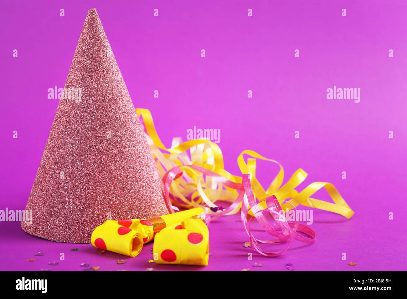 Funny party hat on purple background Stock Photo - Alamy