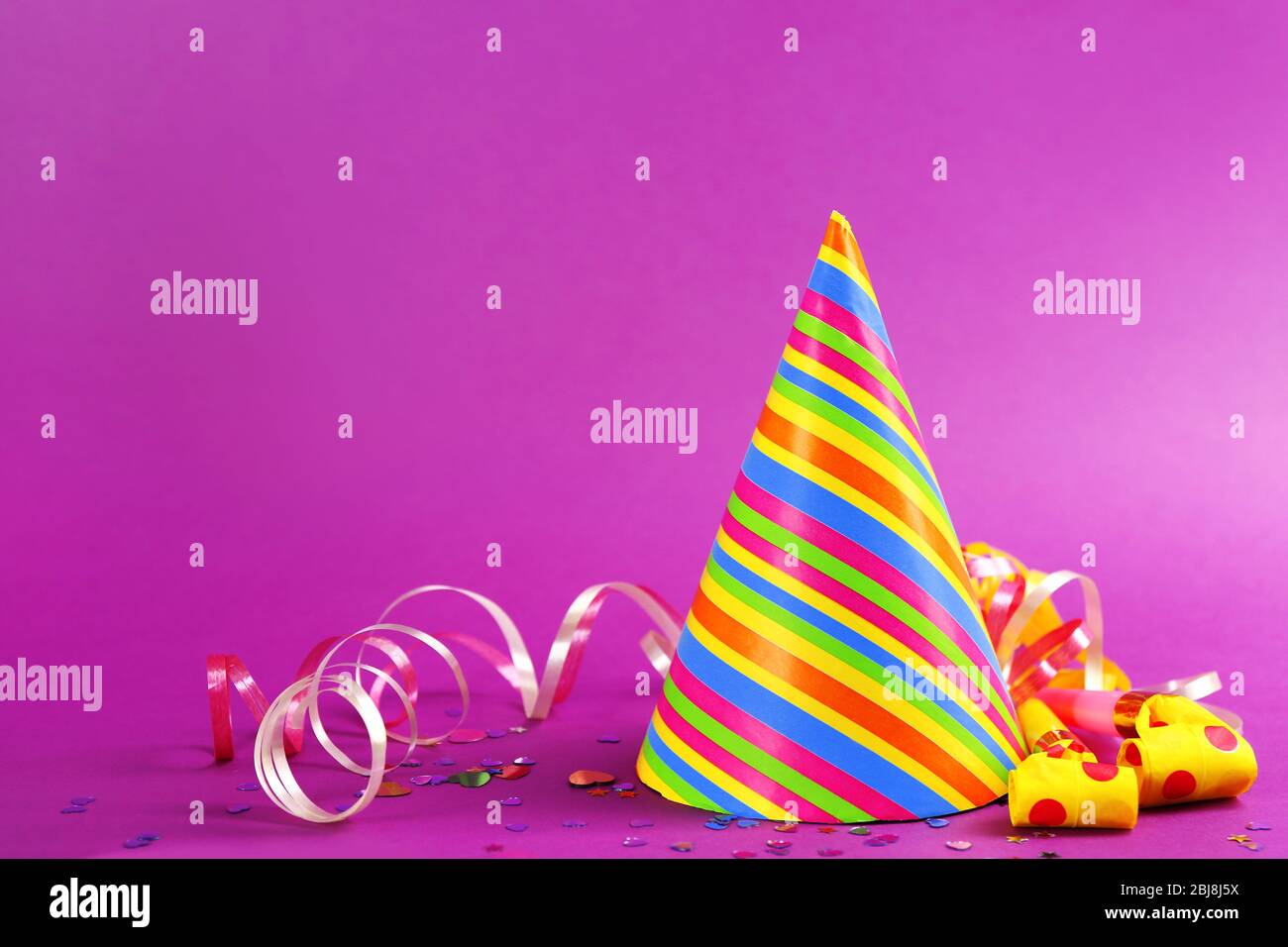 Funny party hat on purple background Stock Photo - Alamy