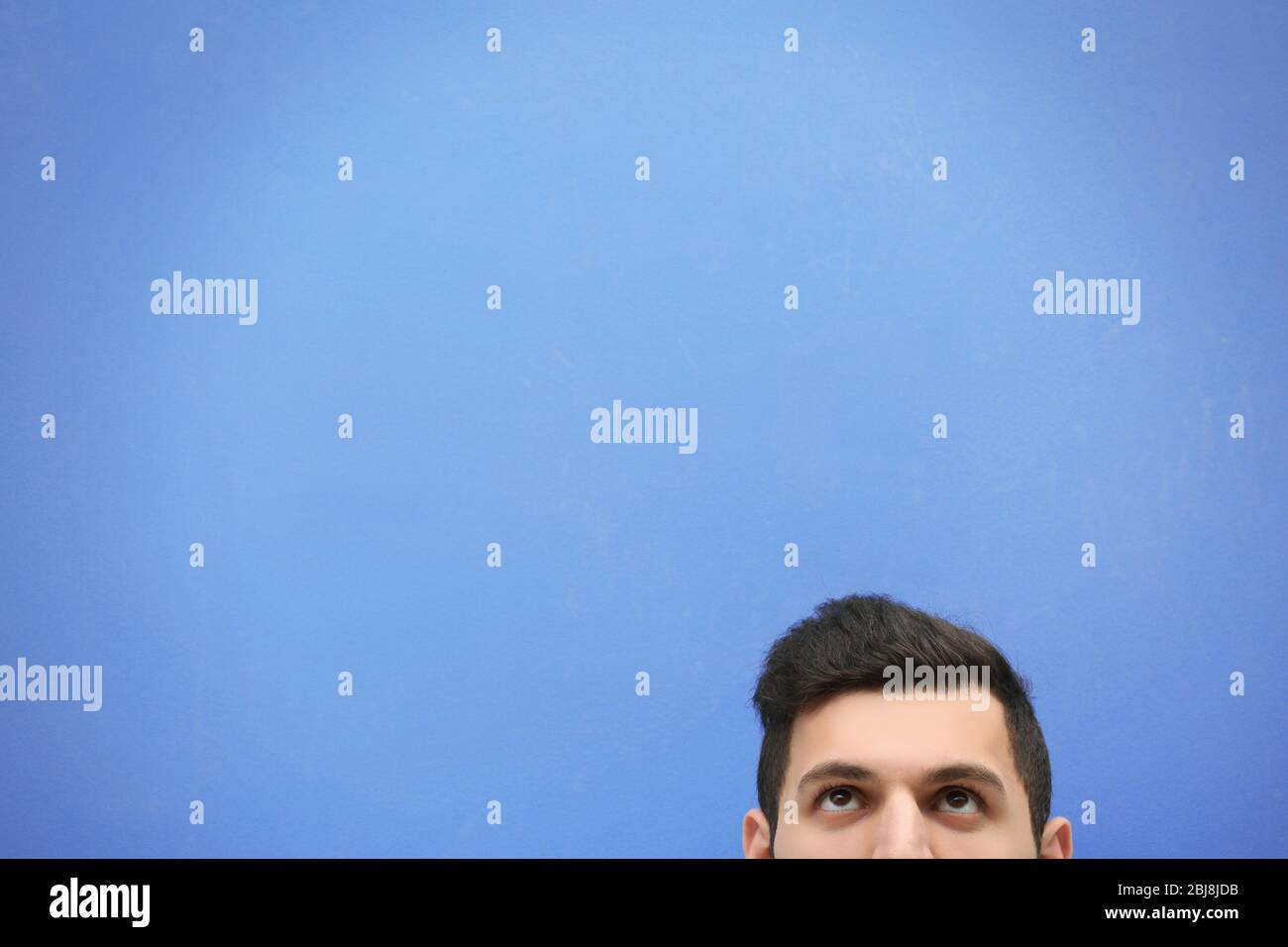 Forehead of a young man against light blue wall Stock Photo - Alamy