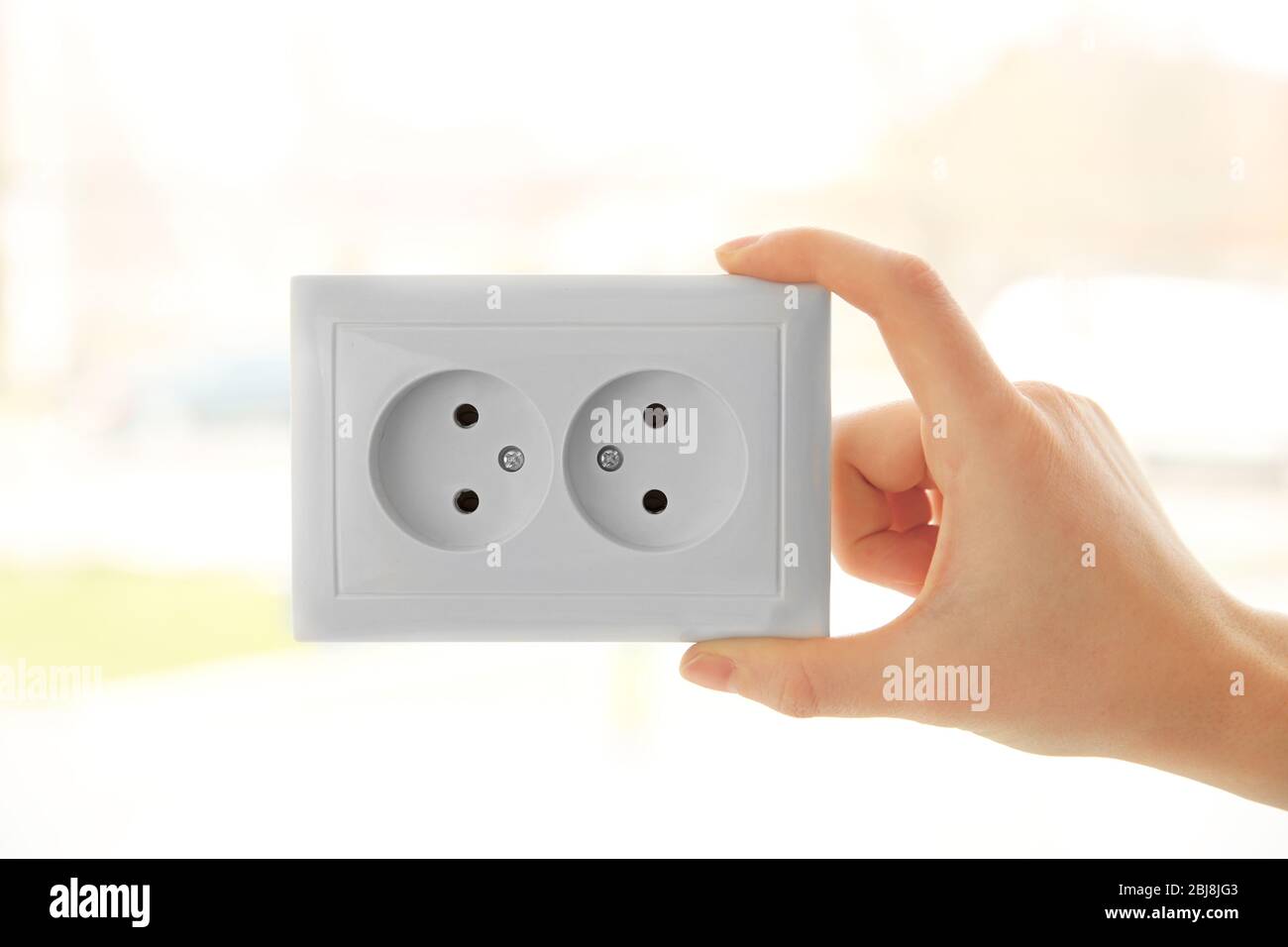 Woman's hand holding power outlet Stock Photo - Alamy