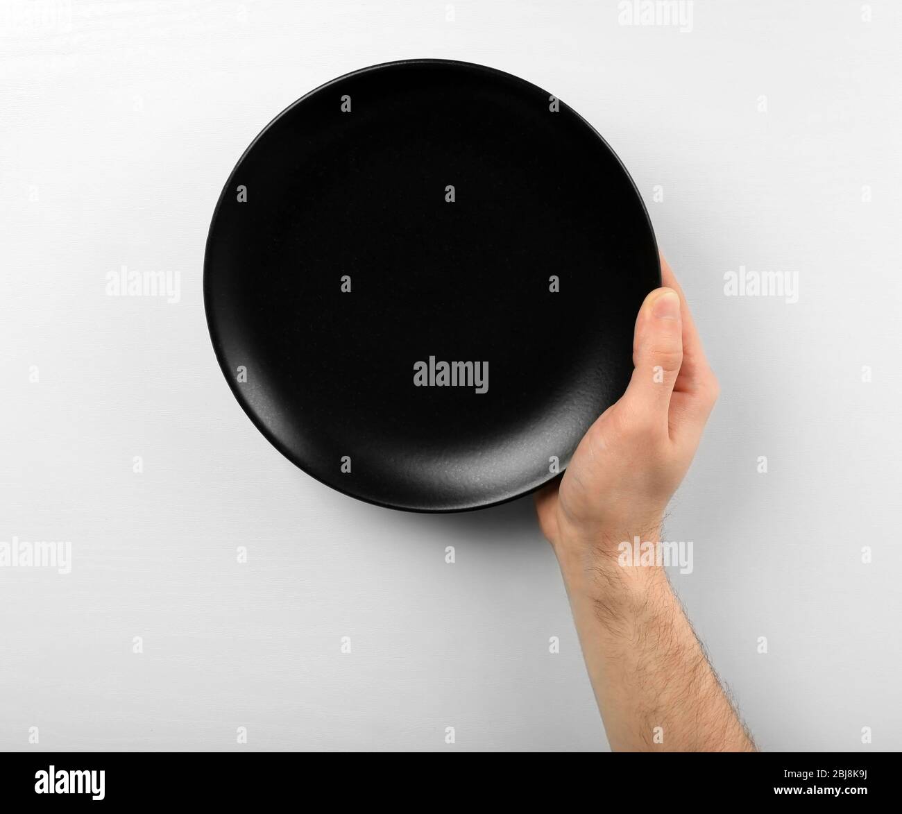 Male hand holding black plate, isolated on white Stock Photo - Alamy