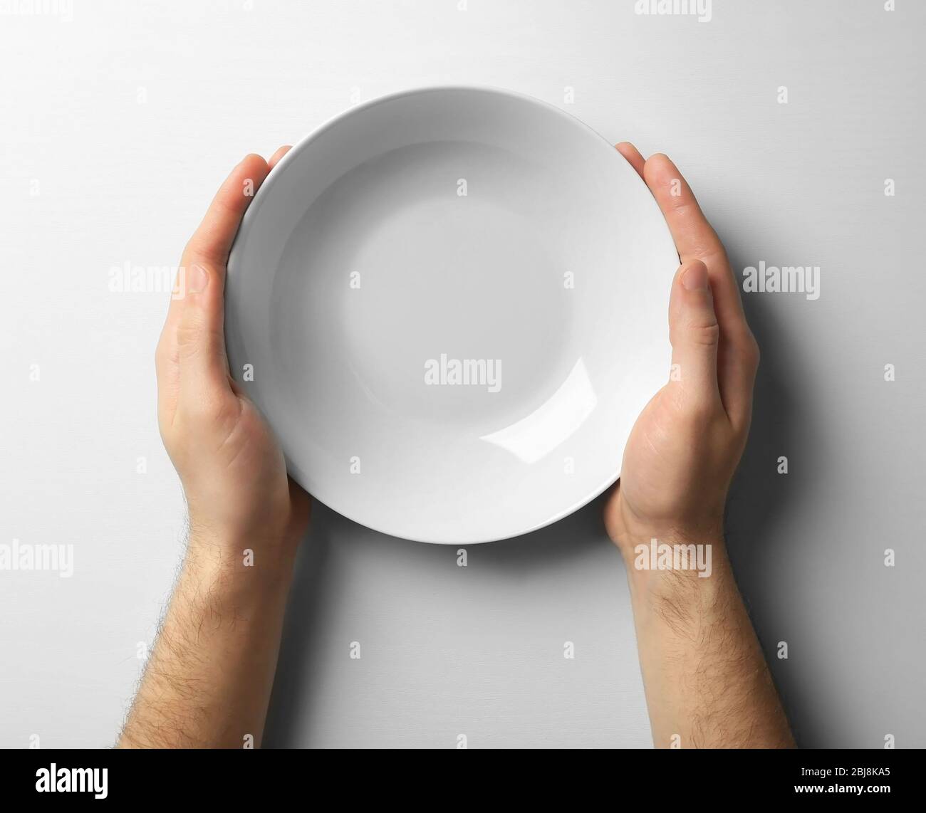 Male hands holding white plate, isolated on white Stock Photo - Alamy