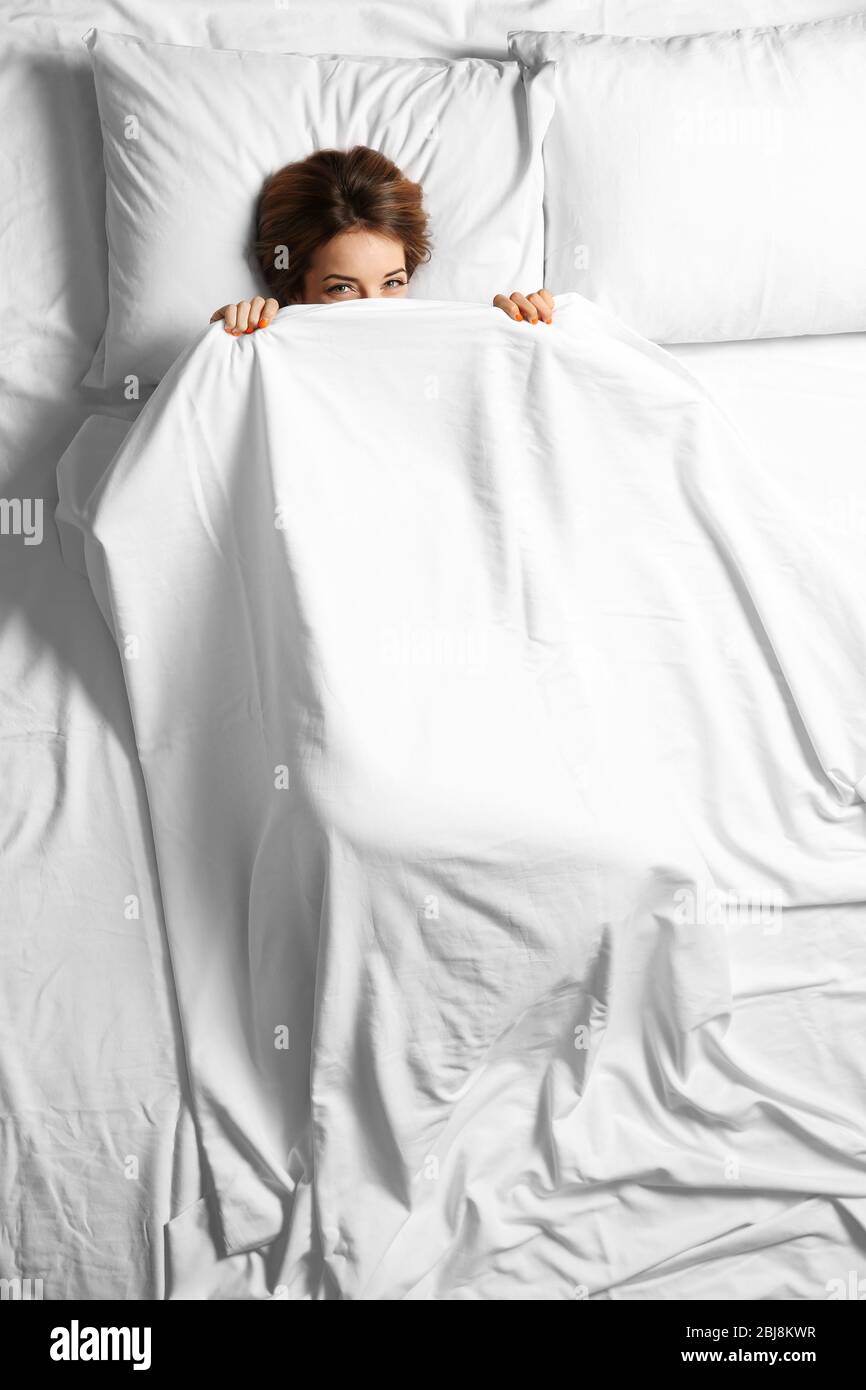 Young woman lying in bed, top view Stock Photo - Alamy