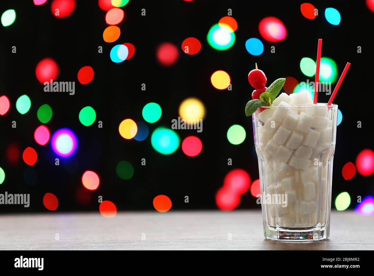 Highball glass with lump sugar on dark bokeh background Stock Photo - Alamy