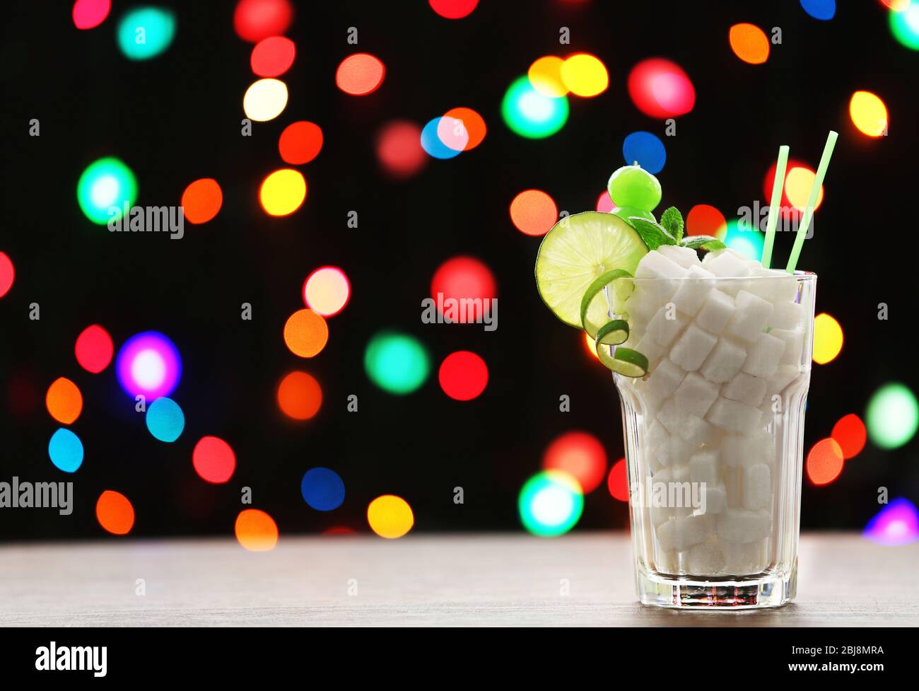 Highball glass with lump sugar on dark bokeh background Stock Photo - Alamy