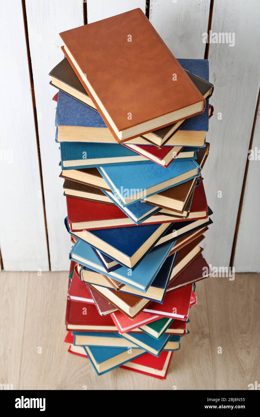 High stack of books on white wooden wall background Stock Photo - Alamy