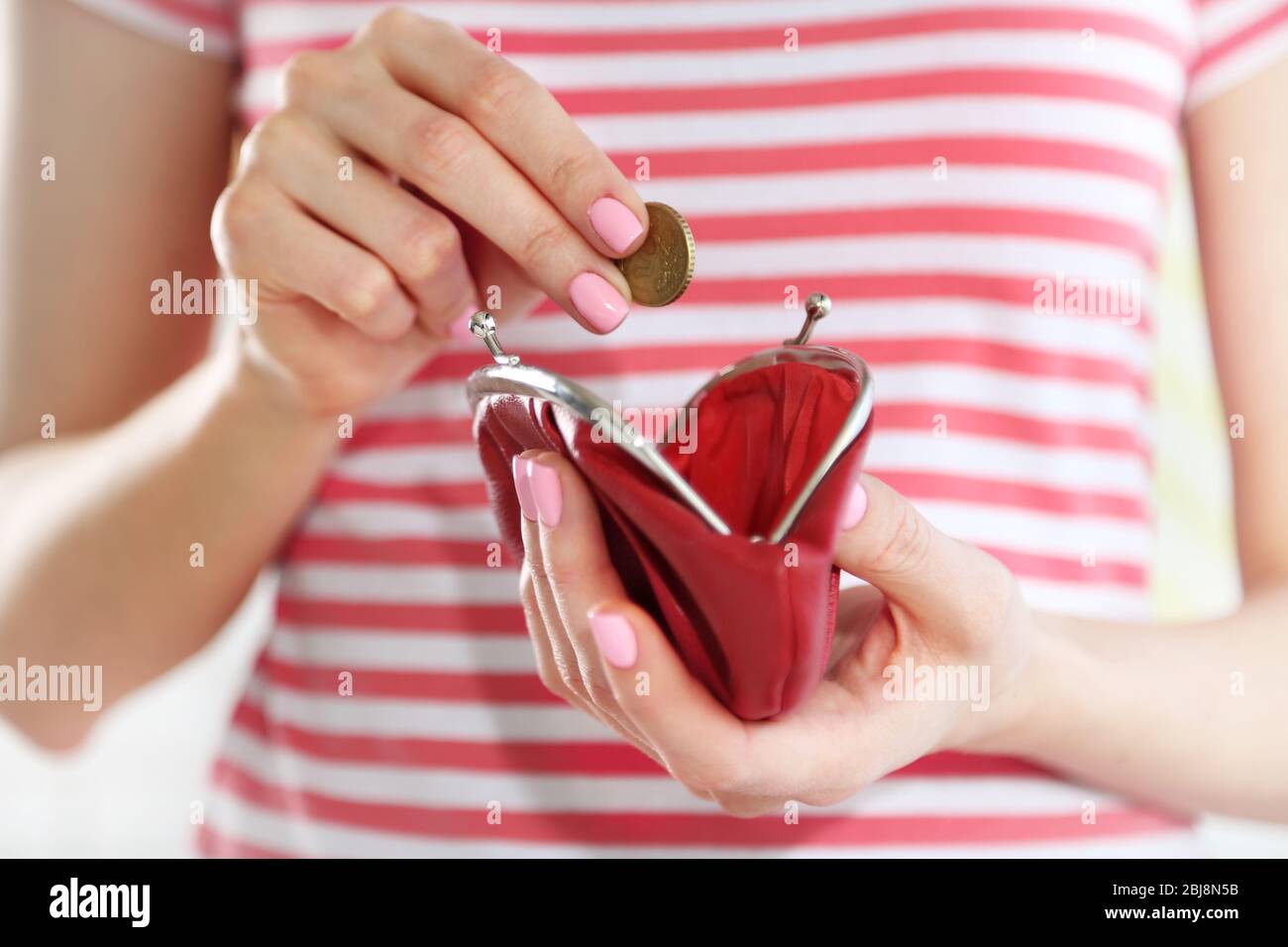 Young woman getting euro coin from purse Stock Photo - Alamy