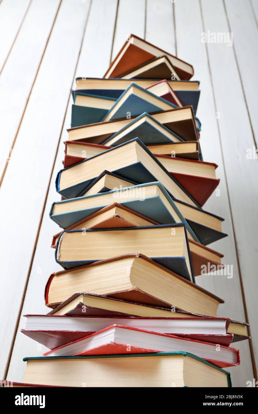 High stack of books on white wooden wall background Stock Photo - Alamy
