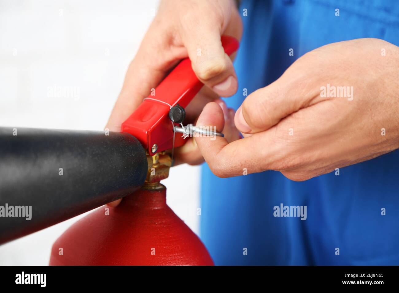 Male hands pulling safety pin of fire extinguisher closeup Stock Photo ...