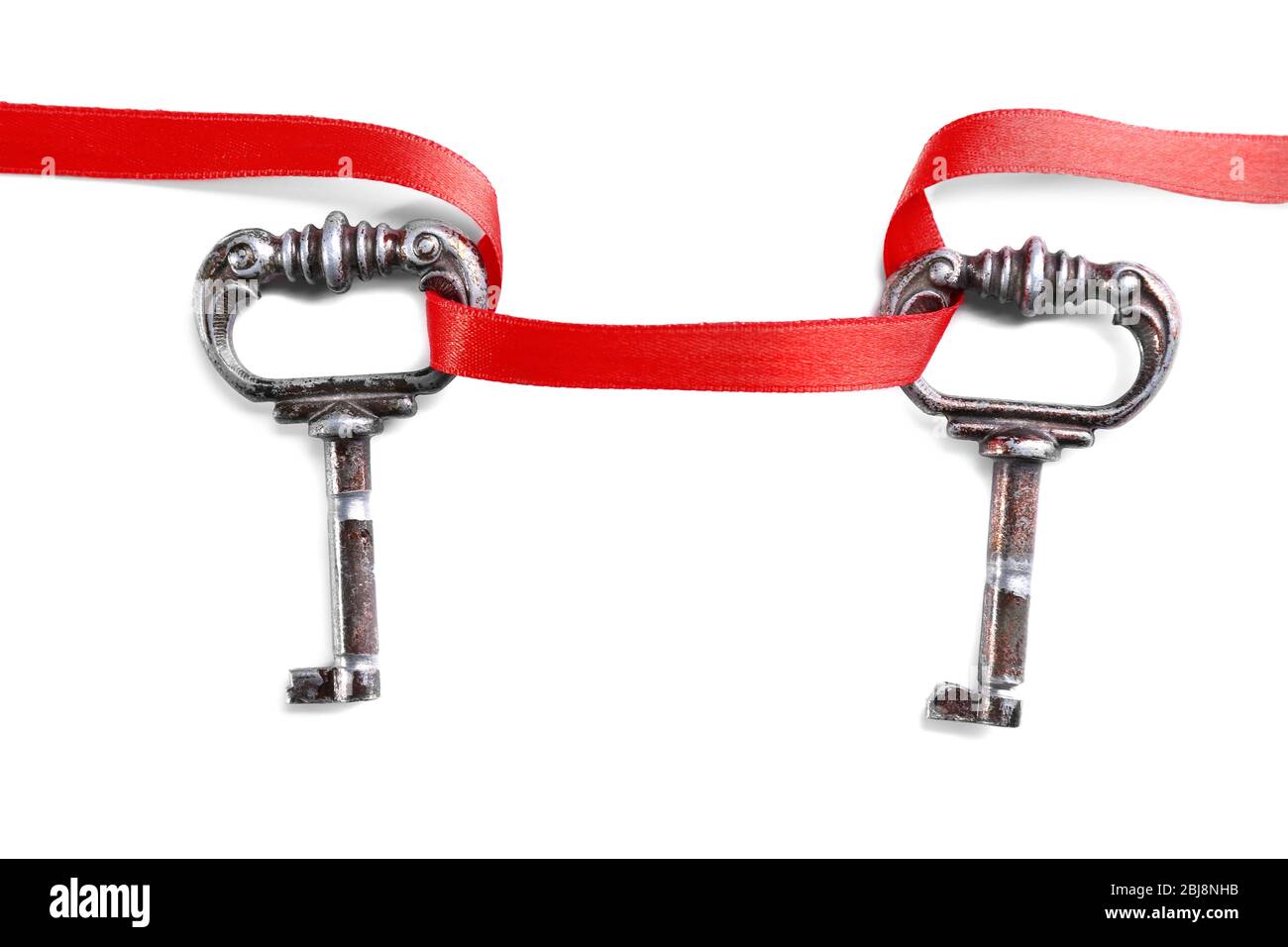 Two vintage keys connected with a red ribbon on a white background ...