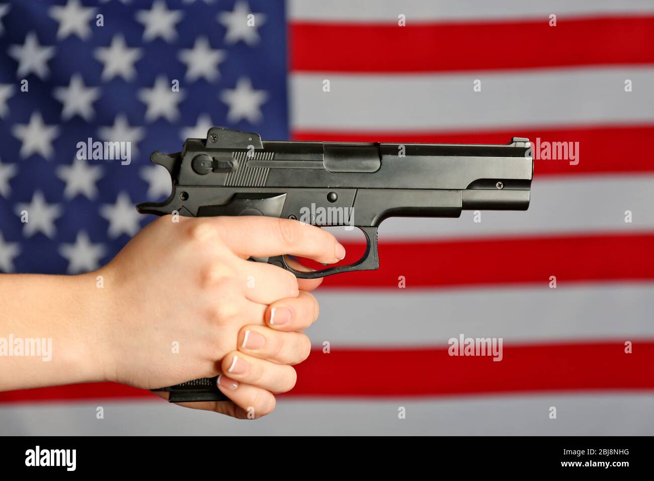 Woman holding handgun on USA national flag background Stock Photo - Alamy
