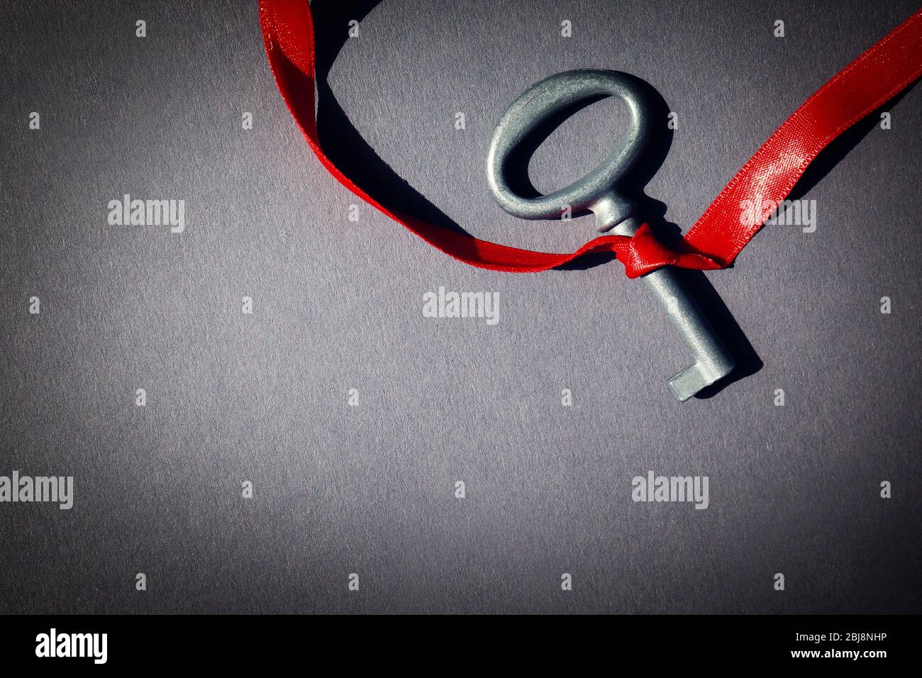 Vintage key with a red ribbon on a grey background Stock Photo - Alamy
