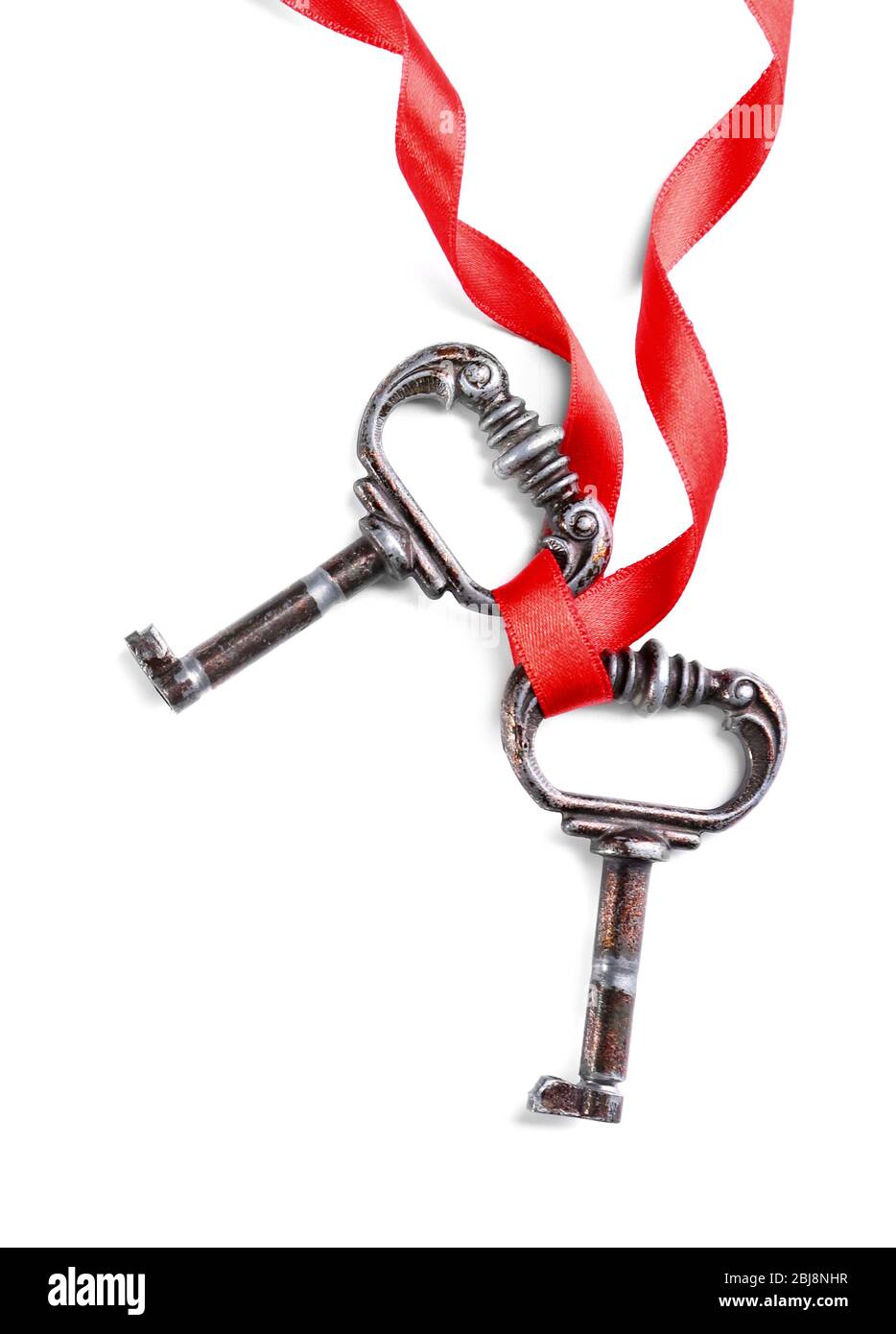 Two vintage keys connected with a red ribbon on a white background ...