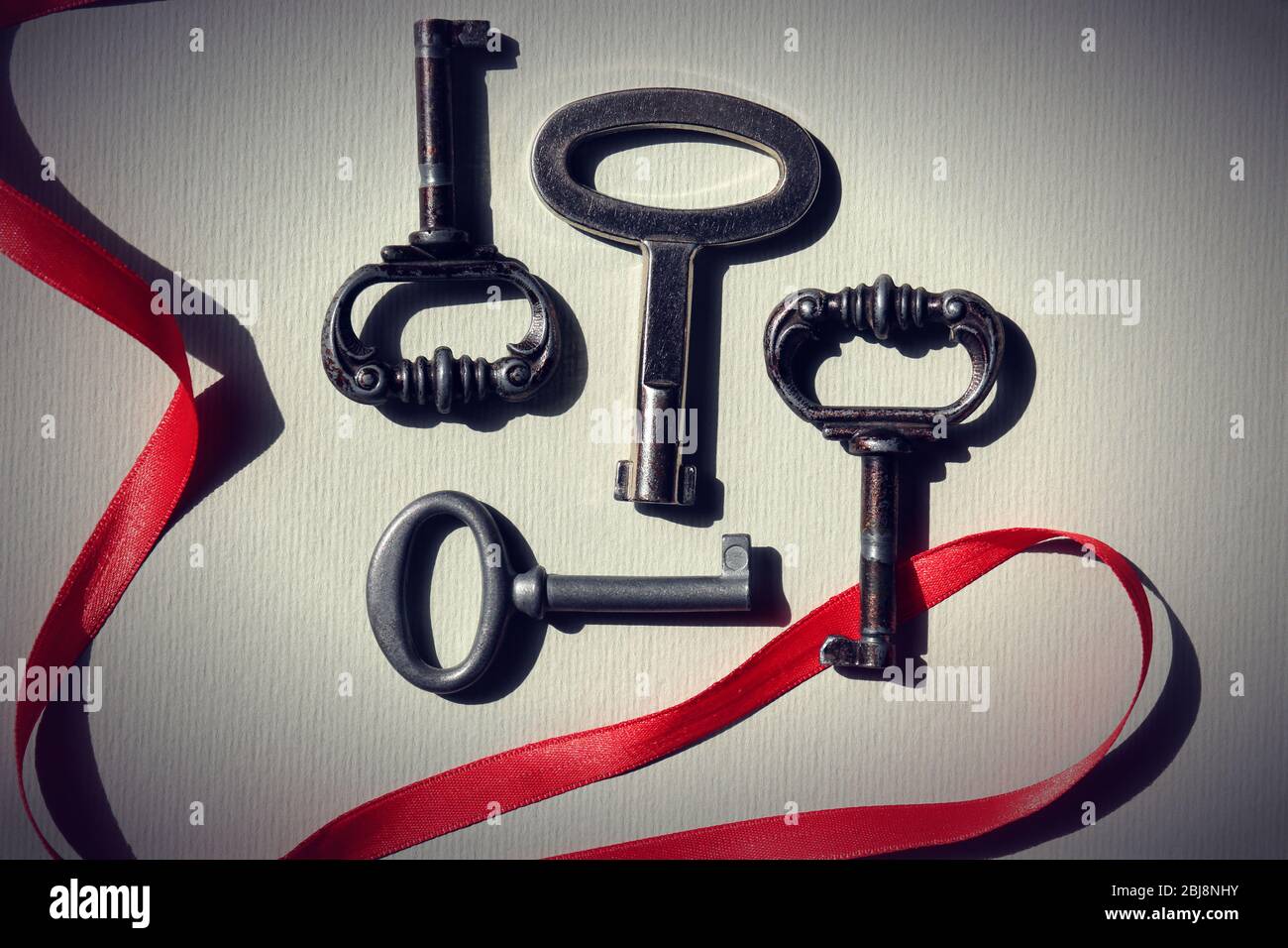 Vintage keys with a red ribbon on light paper background Stock Photo ...