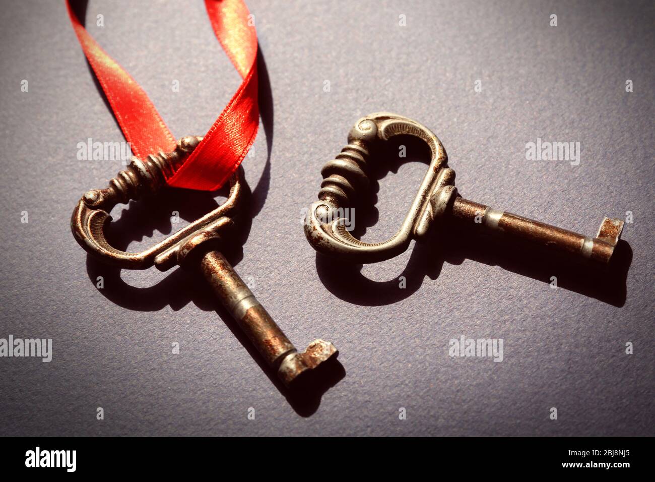 Vintage keys with a red ribbon on dark blue background Stock Photo - Alamy