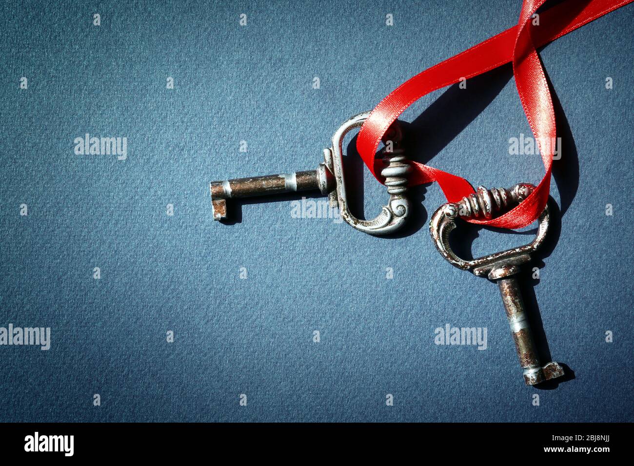 Vintage keys with a red ribbon on dark blue background Stock Photo - Alamy