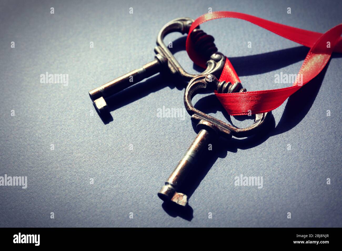 Vintage keys with a red ribbon on dark blue background Stock Photo - Alamy