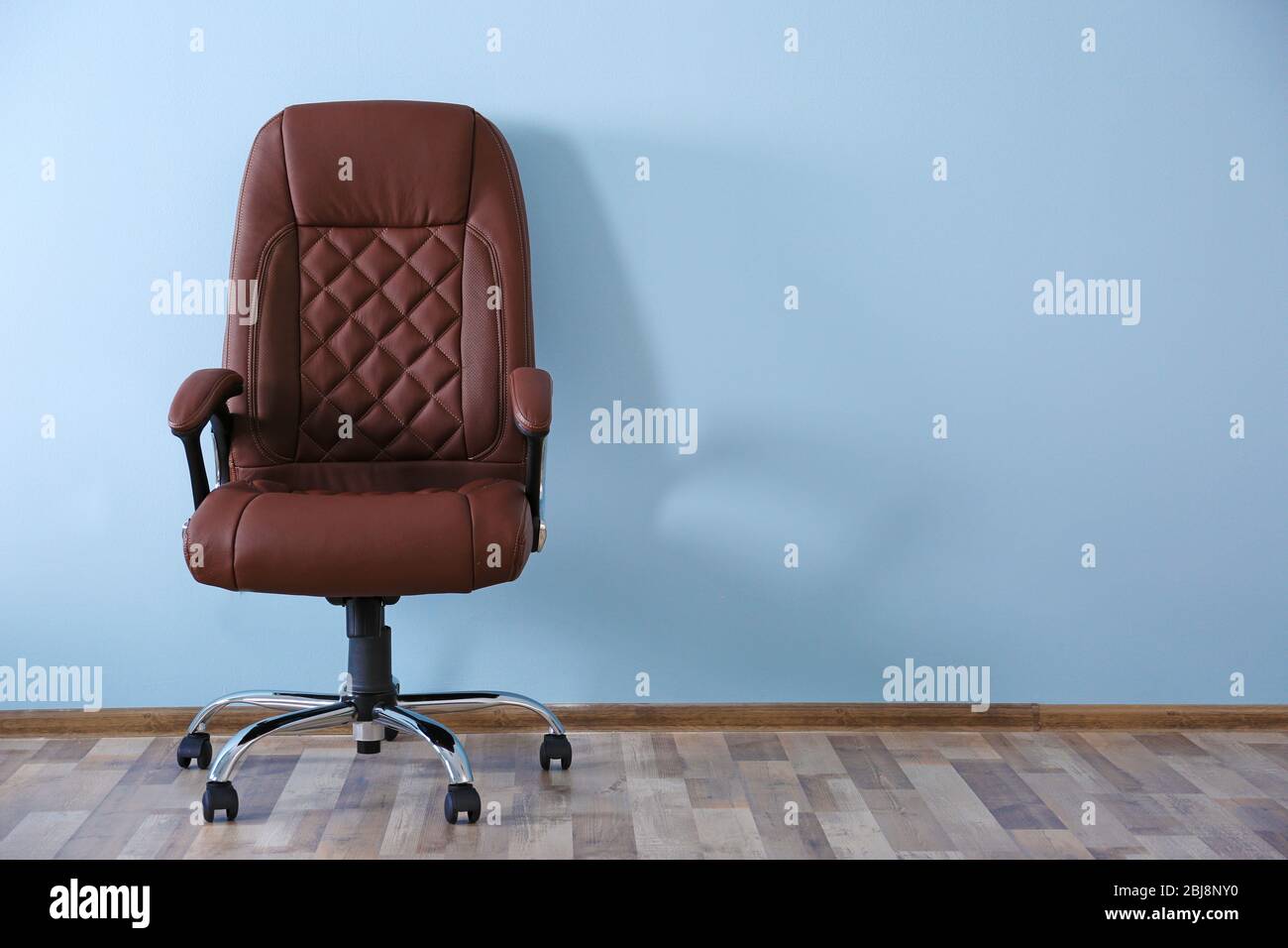 New office chair on wall background Stock Photo - Alamy