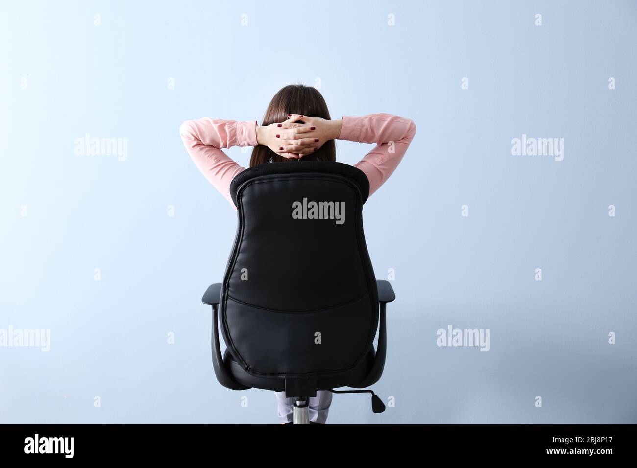 Woman sitting back on the office chair indoors Stock Photo - Alamy