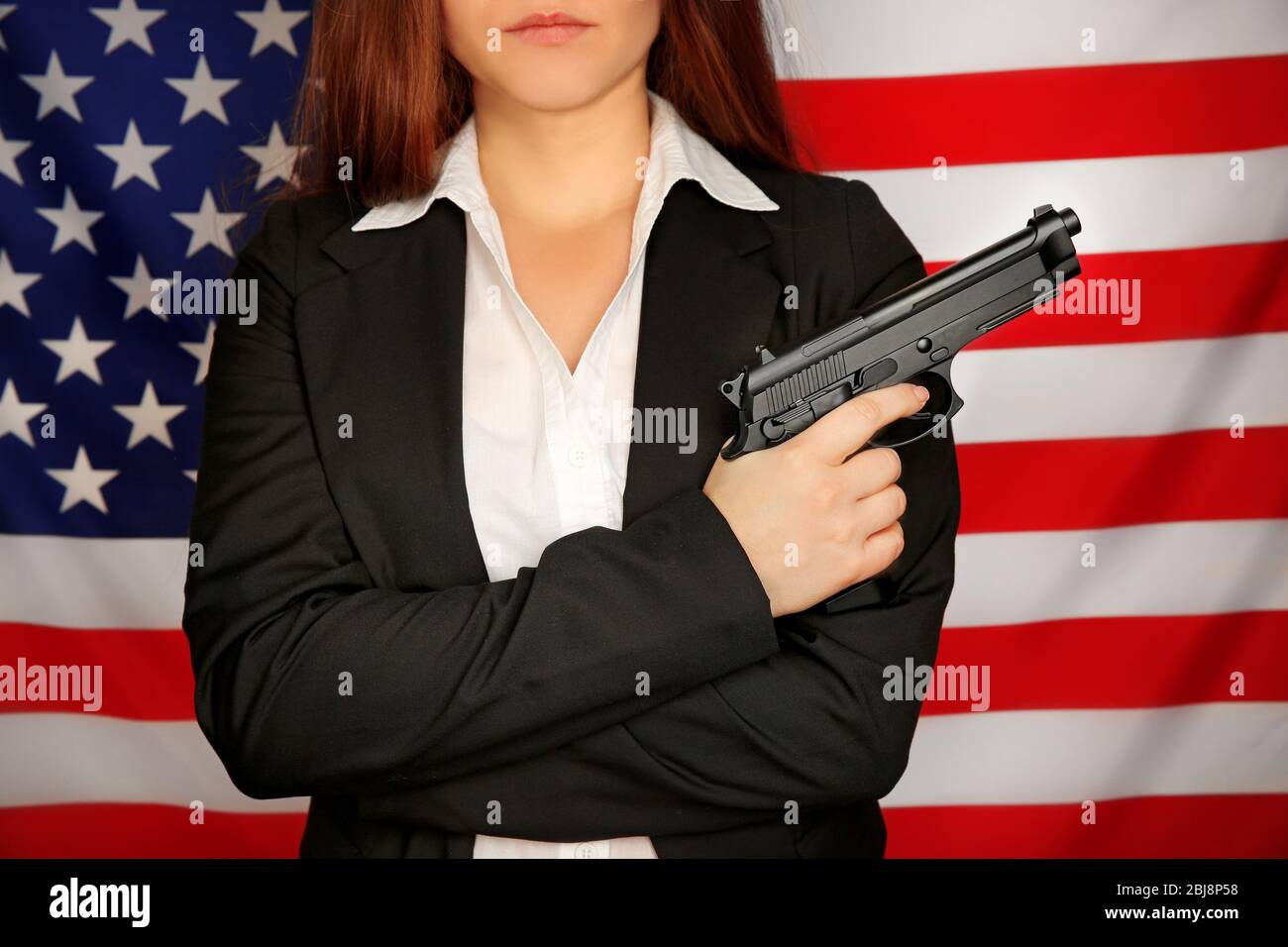 Woman holding gun on USA flag background Stock Photo - Alamy