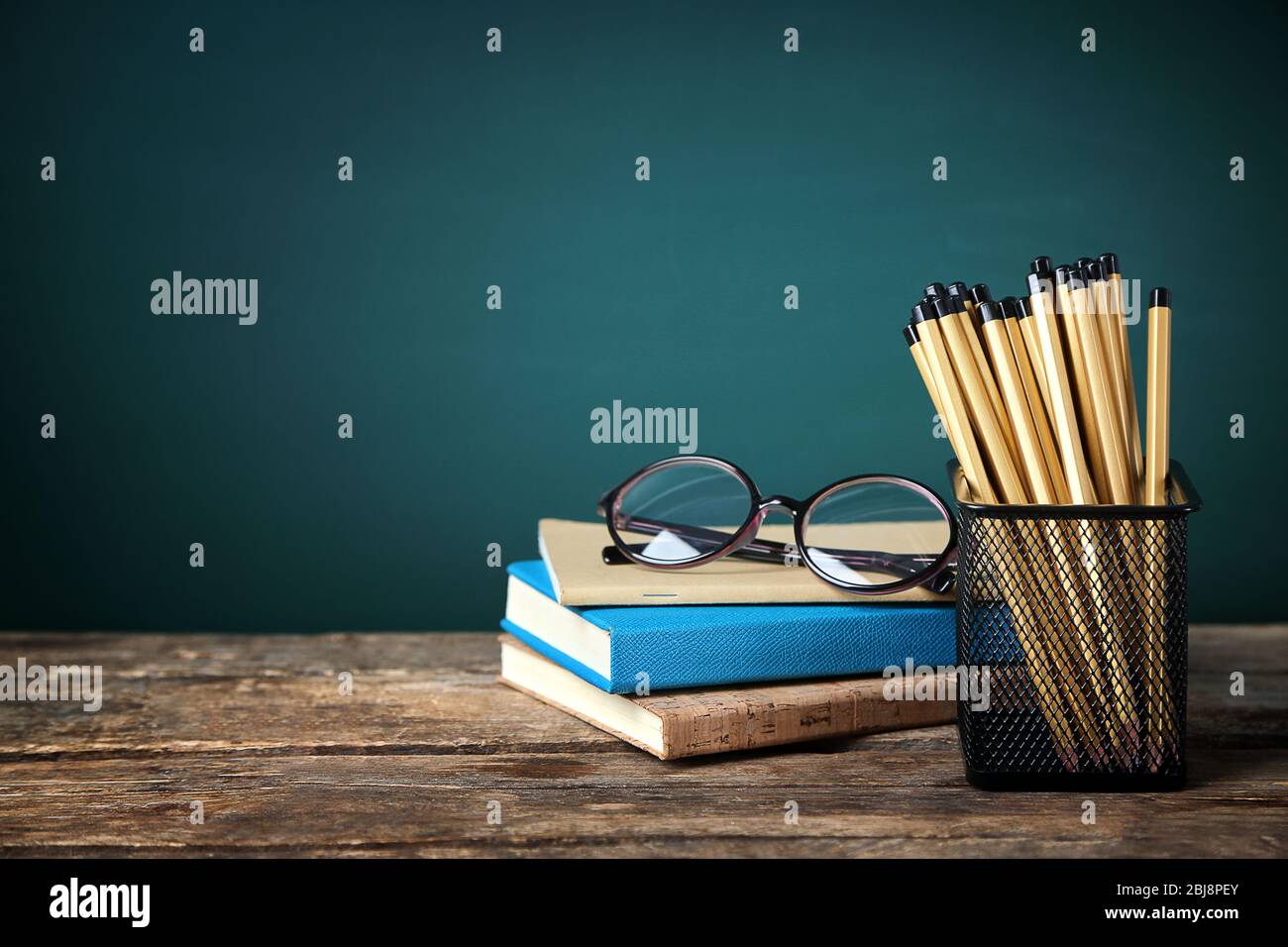 Many pencils in the metal holder on wooden table on green board ...