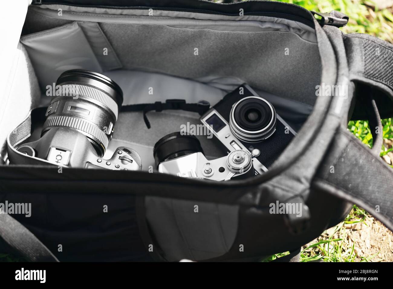 Modern and old cameras in open backpack outdoors Stock Photo - Alamy